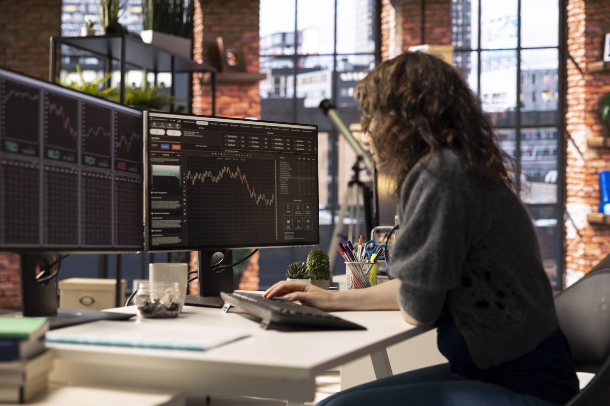 Young woman studies stock trading charts on her computer - FAD Magazine